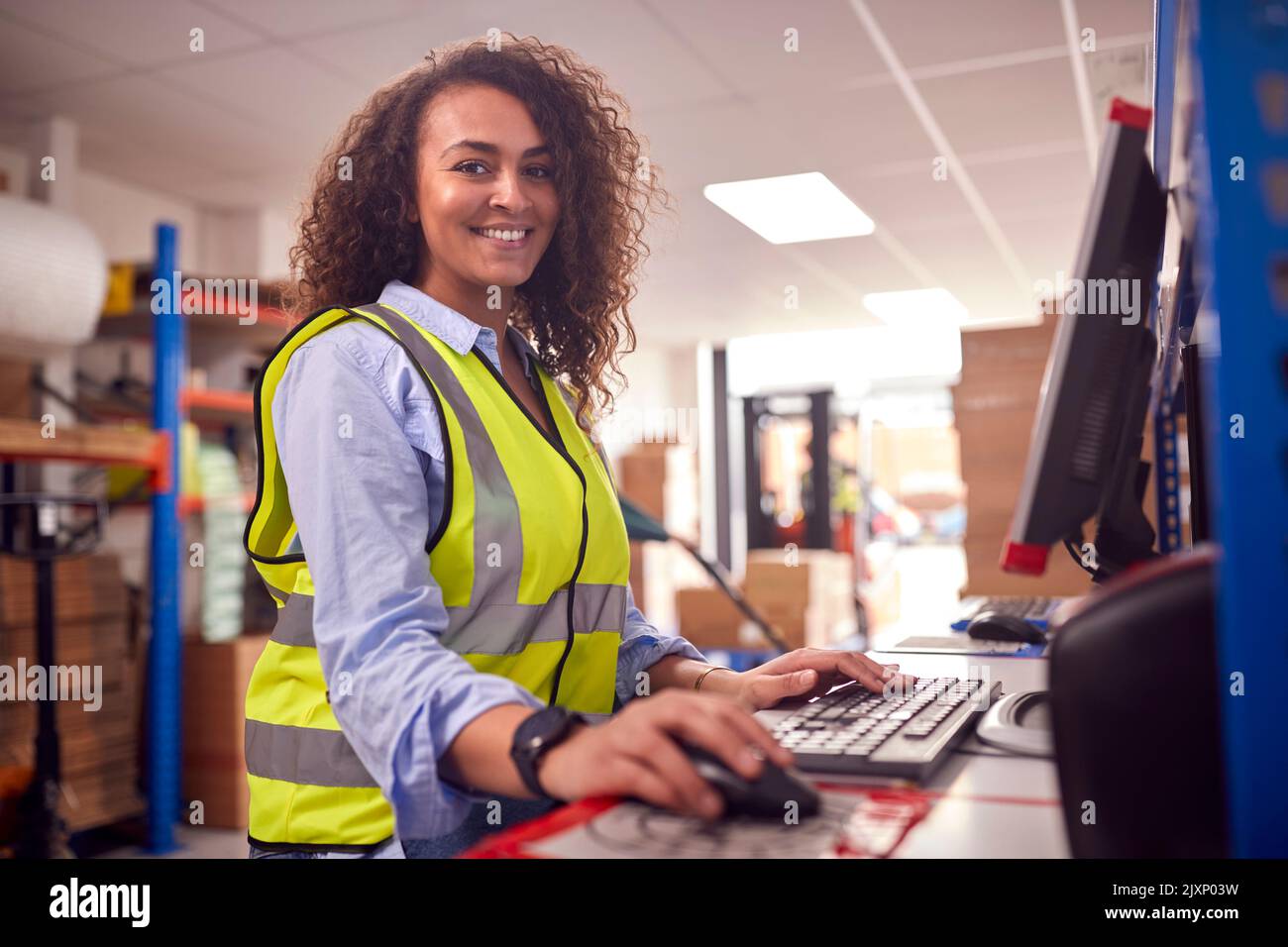 Portrait Of Female Worker In Busy Modern Warehouse Working On Computer ...