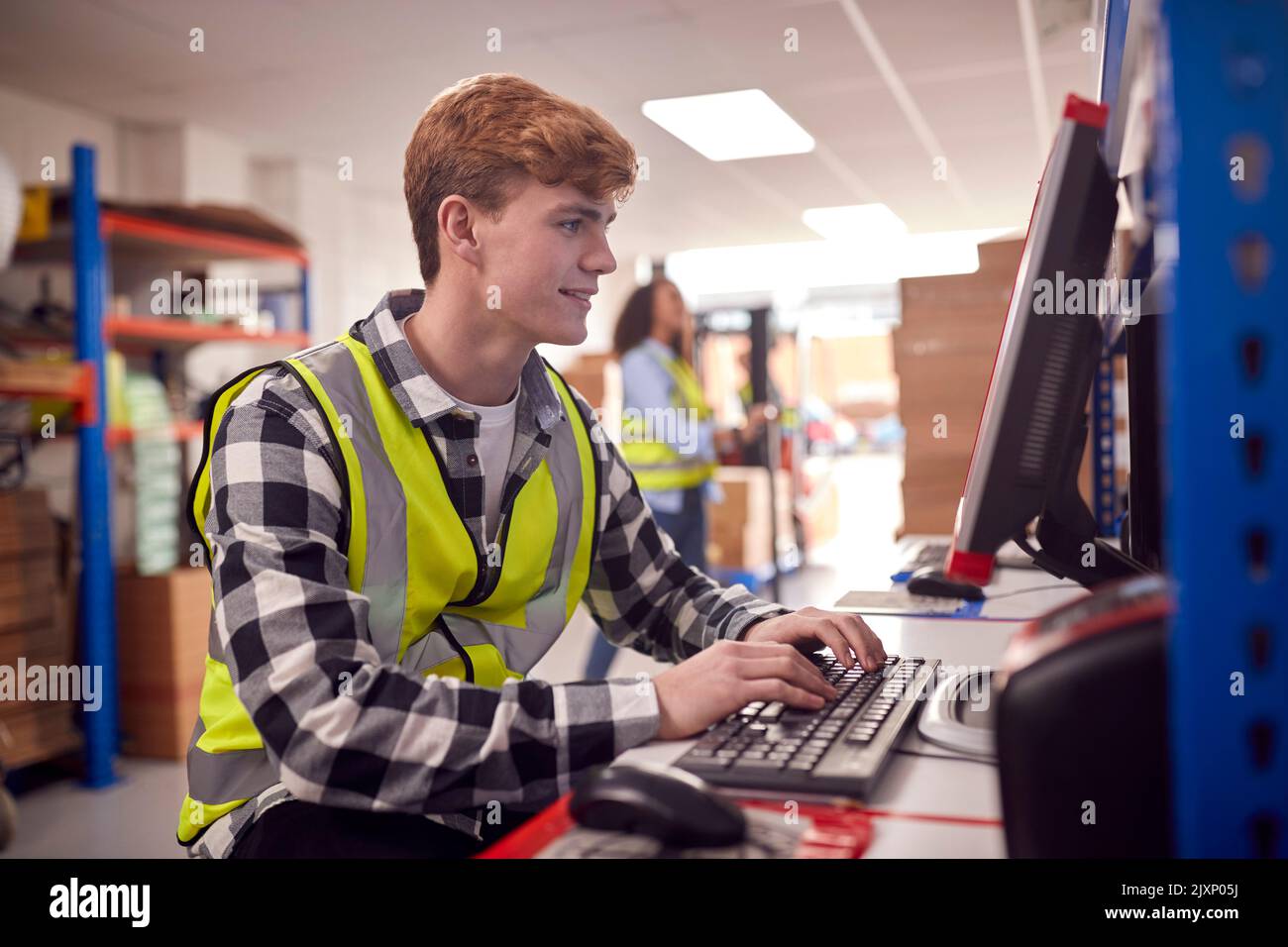 Male Intern Working In Busy Modern Warehouse On Computer Terminal Stock ...