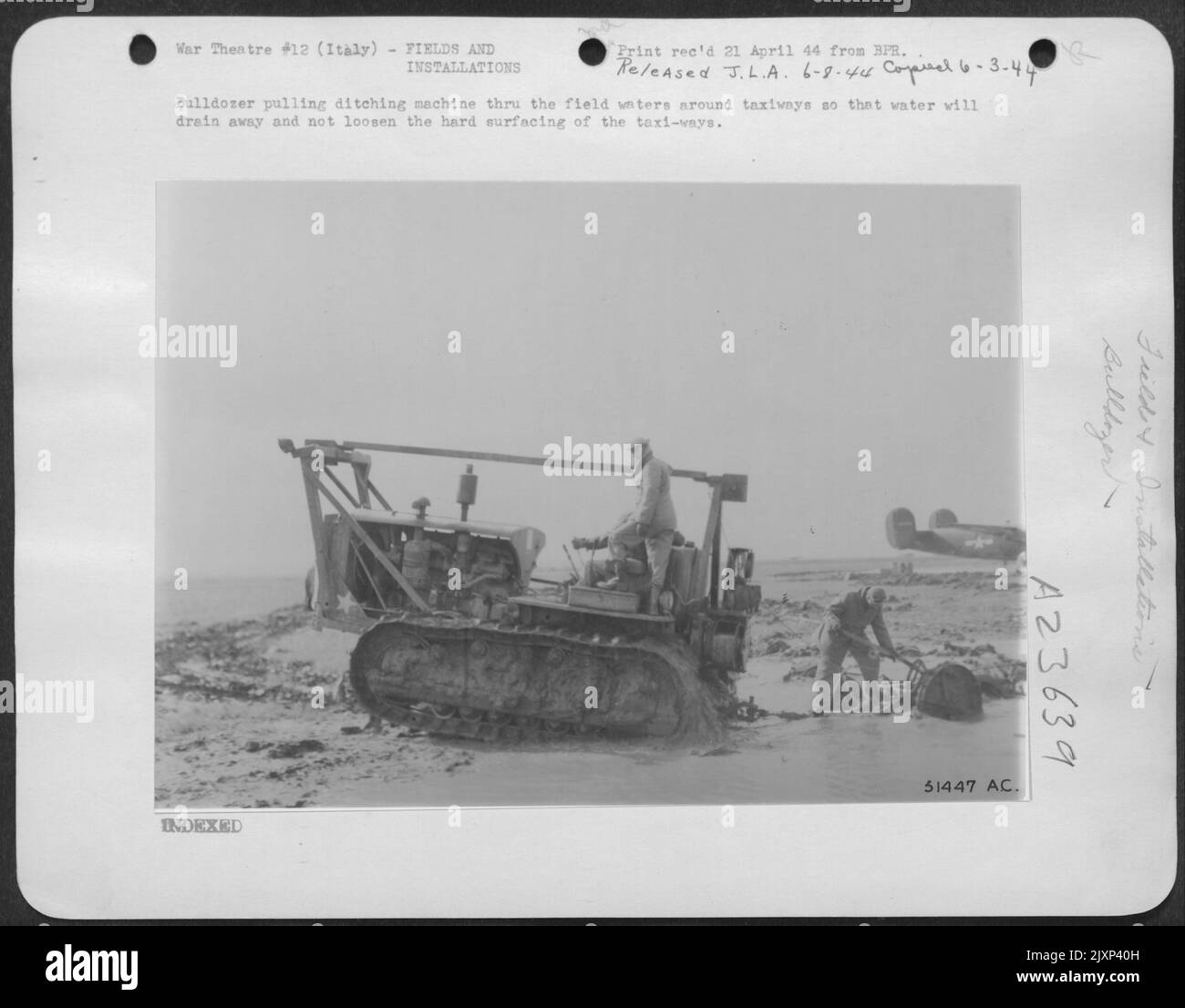 Bulldozer pulling ditching machine thru the field waters around ...
