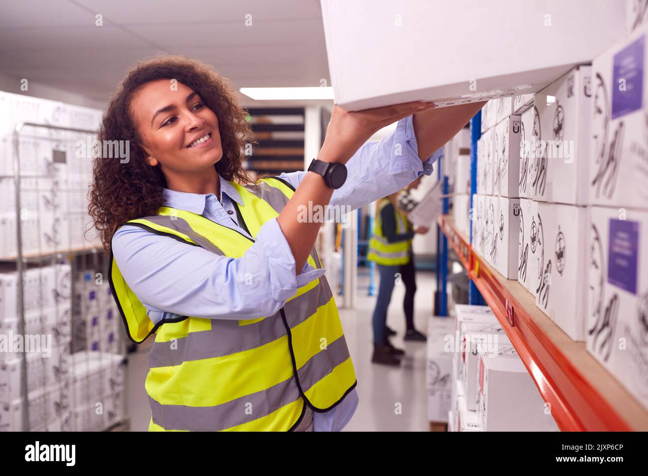 Female Worker Inside Busy Warehouse Putting Box Onto Shelf Stock Photo ...