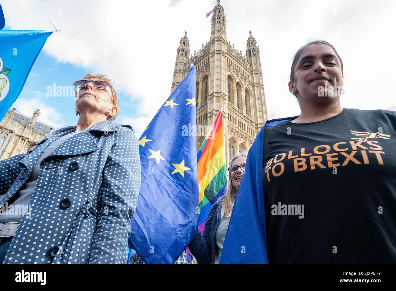 People are seen protesting outside parliament with banners and flags. A ...