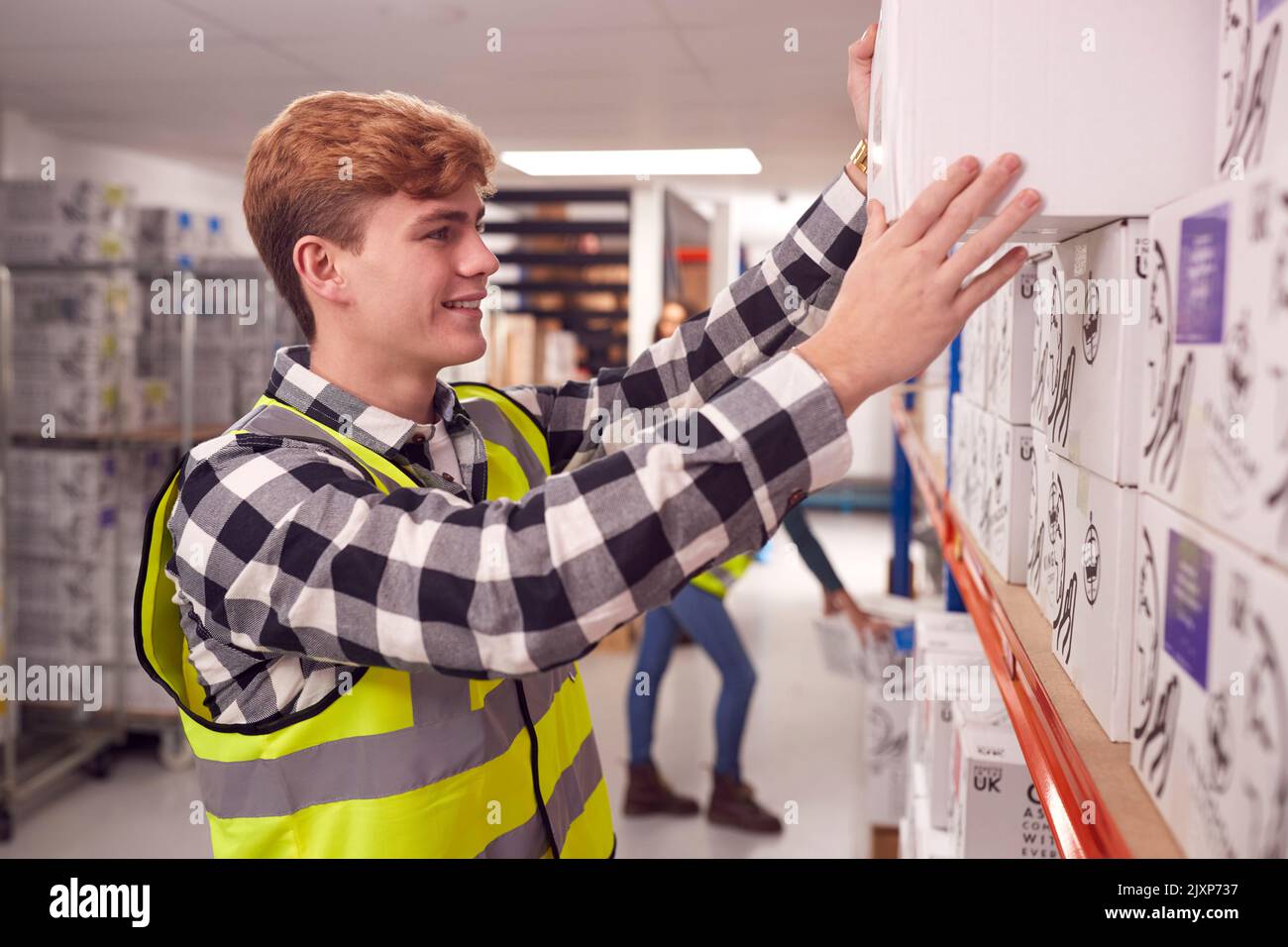 Male Worker Inside Busy Warehouse Putting Box Onto Shelf Stock Photo ...