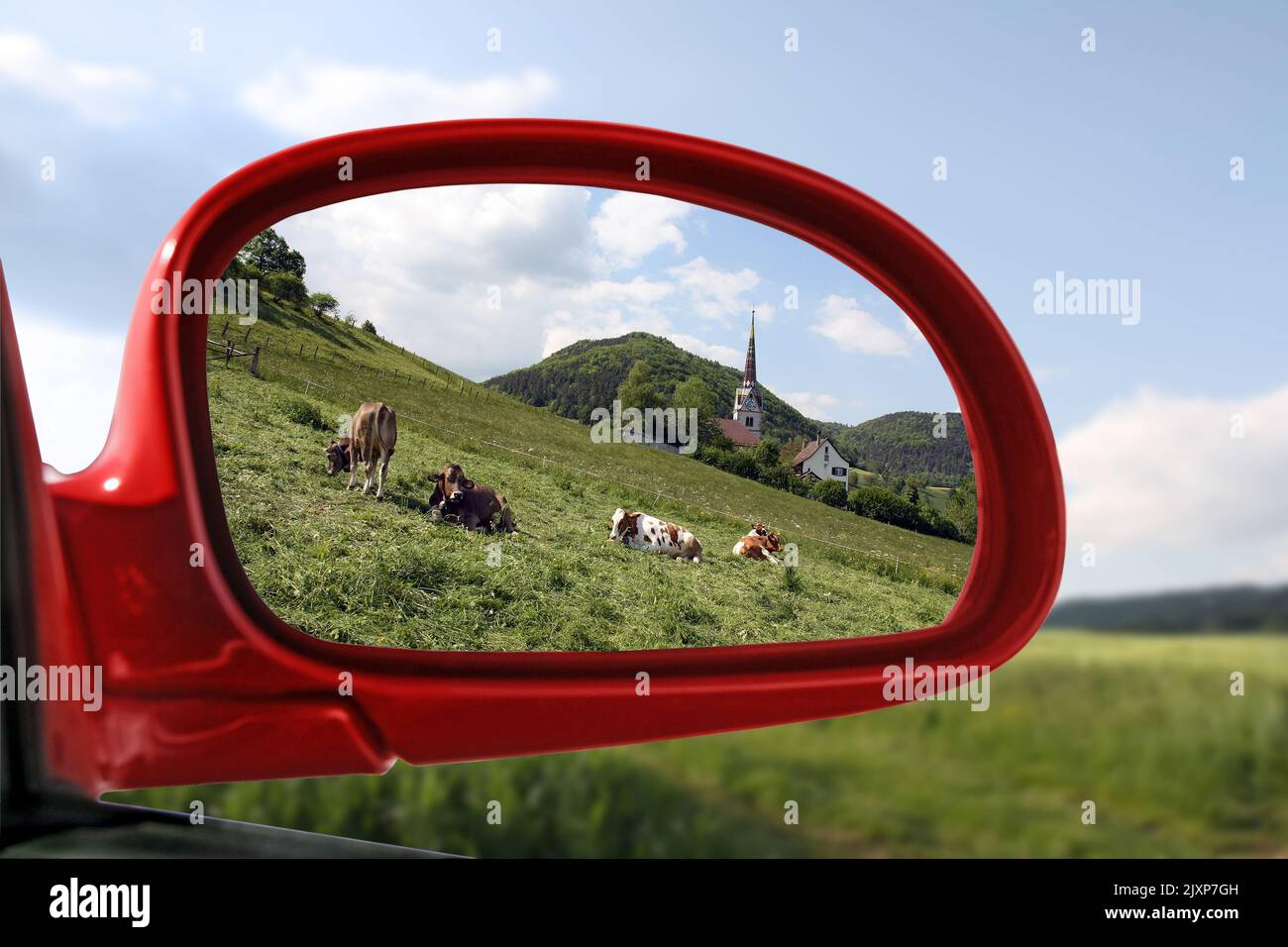 Landscape reflected in the rear view mirror of a red car - summer ...