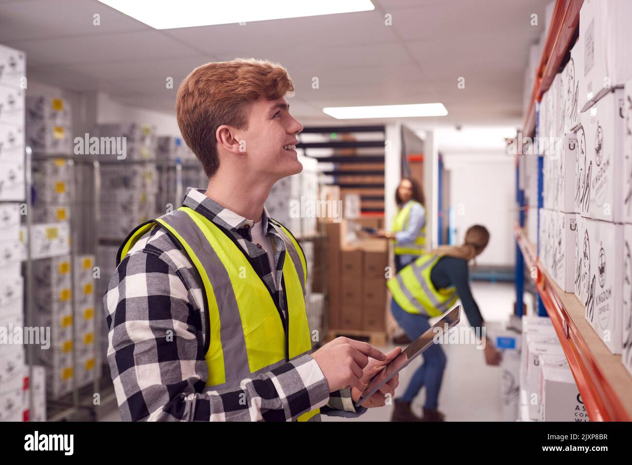 Male Worker Inside Busy Warehouse Checking Stock On Shelves Using ...