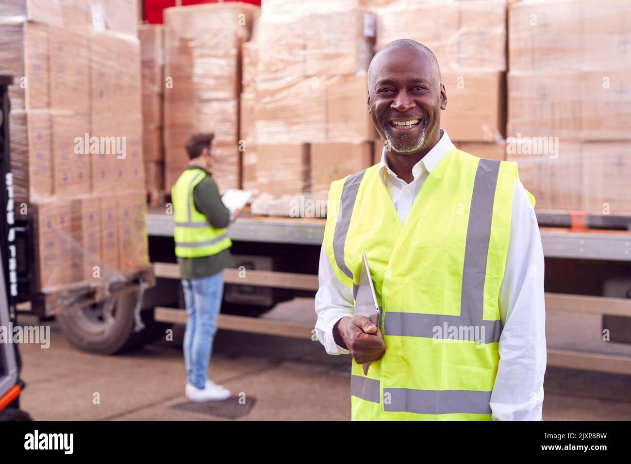 Portrait Of Male Freight Haulage Manager Standing By Truck Being Loaded By Fork Lift Stock Photo ...