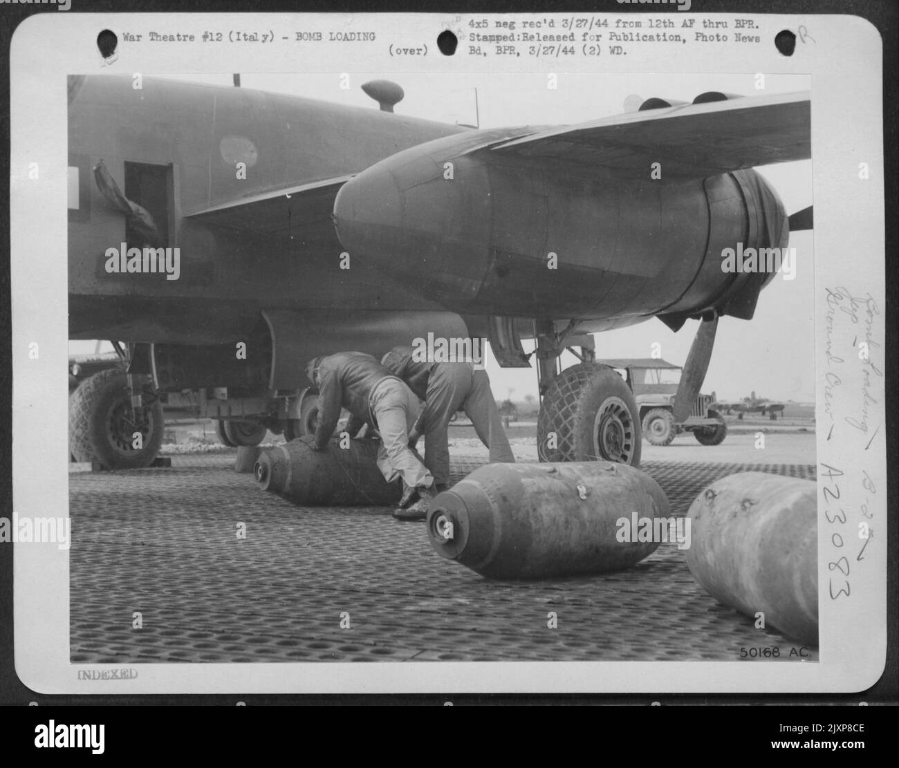 Armament workers roll a thousand pounder under the bomb bay of a B-25 ...