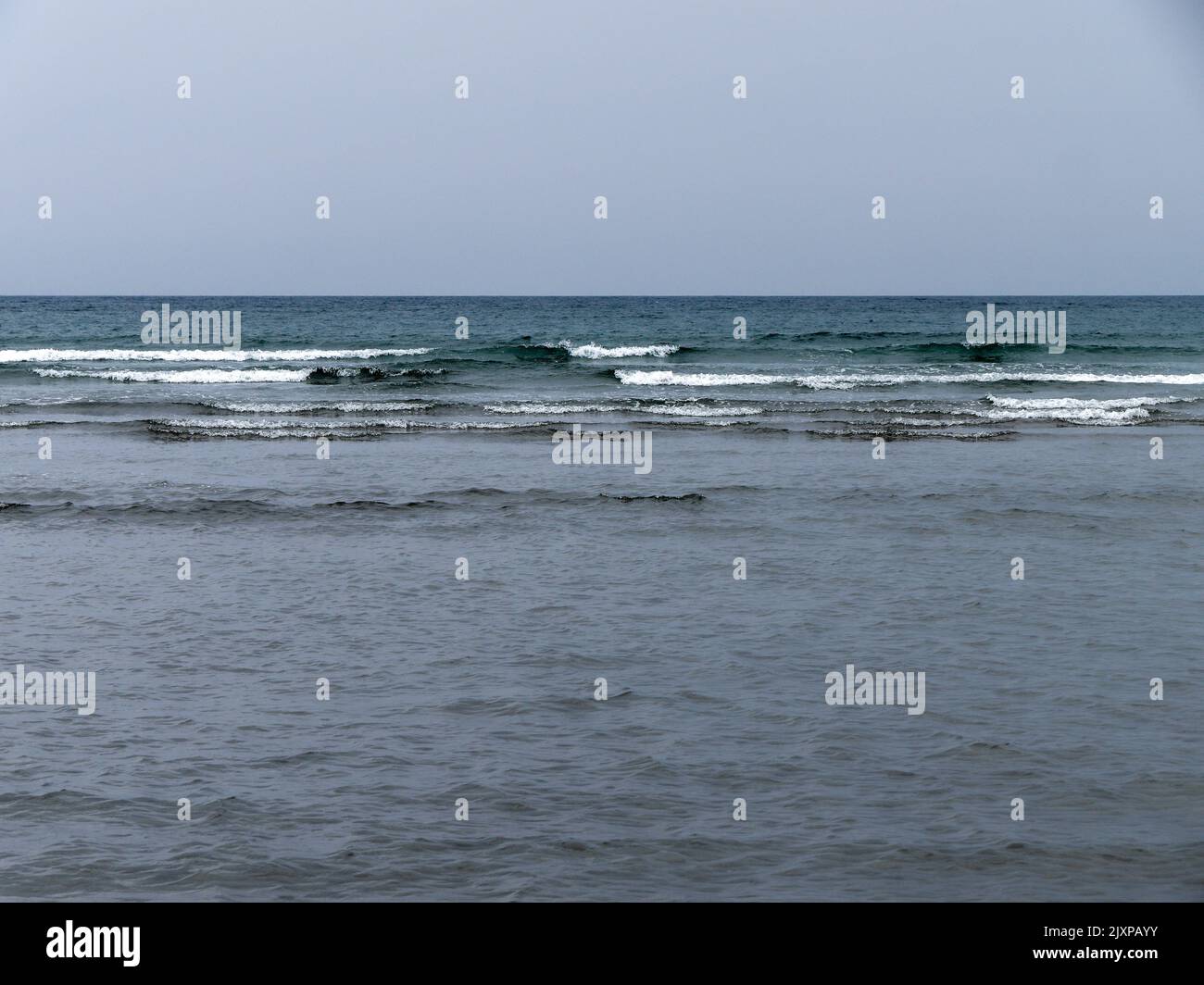 Waves on the sea surface on a cold cloudy day. The horizon line over ...