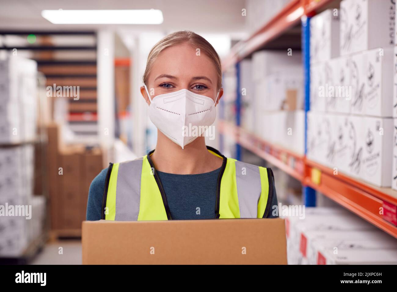 Portrait Of Female Worker Wearing PPE Face Mask Holding Box Inside ...