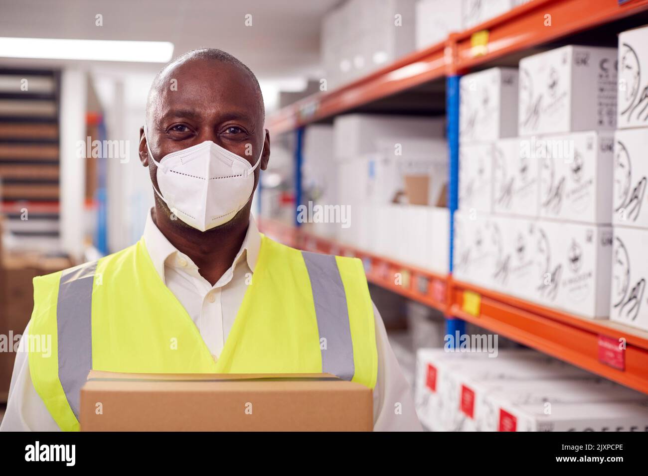 Portrait Of Male Worker Wearing PPE Face Mask Holding Box Inside ...