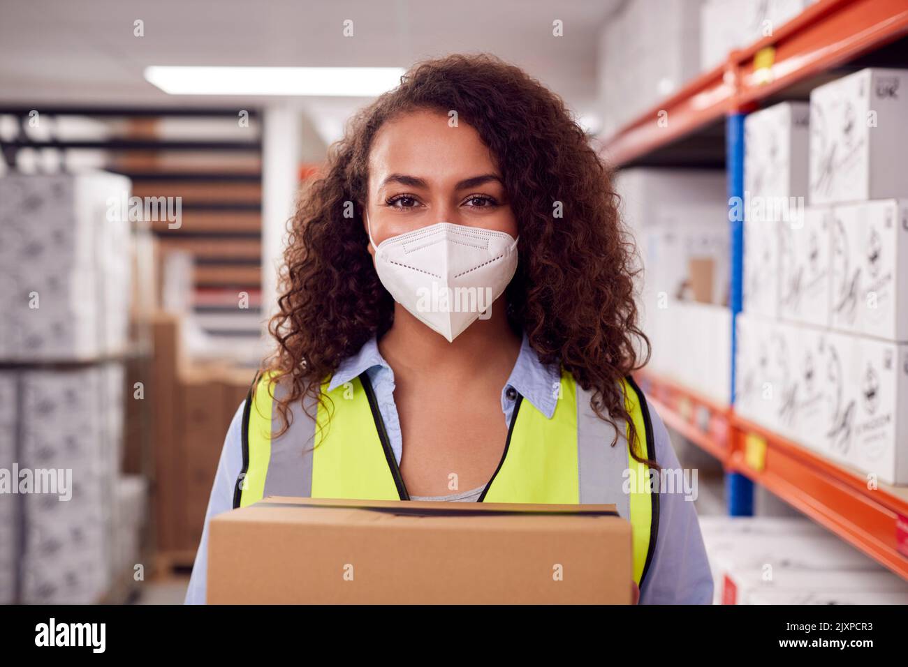 Portrait Of Female Worker Wearing PPE Face Mask Holding Box Inside ...