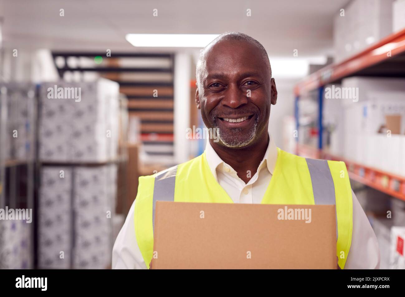 Portrait Of Smiling Male Worker Holding Box Inside Warehouse Stock ...