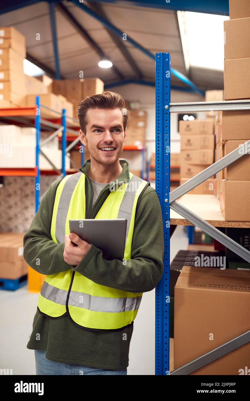 Male Worker Wearing High-Vis Vest Inside Warehouse Checking Stock On ...