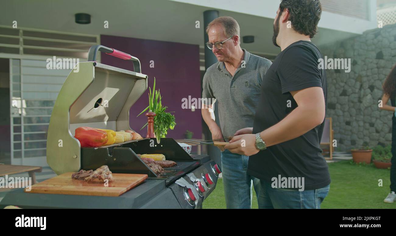 Barbecue chef preparing food at grill in garden backyard party. Father ...