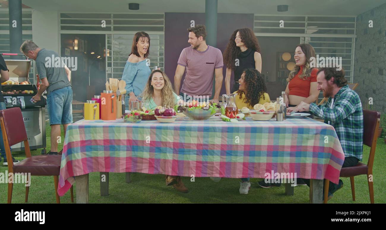 Family meeting at backyard barbecue party. BBQ table. Diverse friends ...
