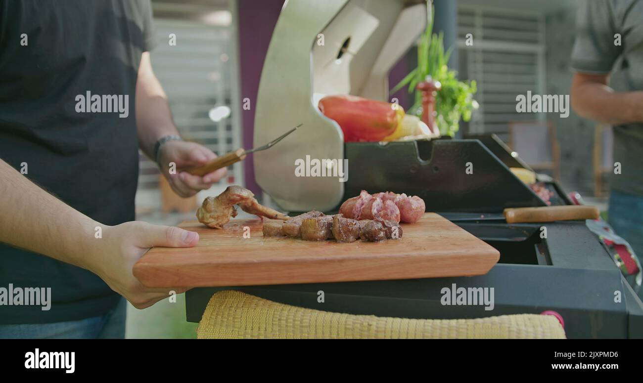 Barbecue chef serving food to friends and family at BBQ home backyard ...