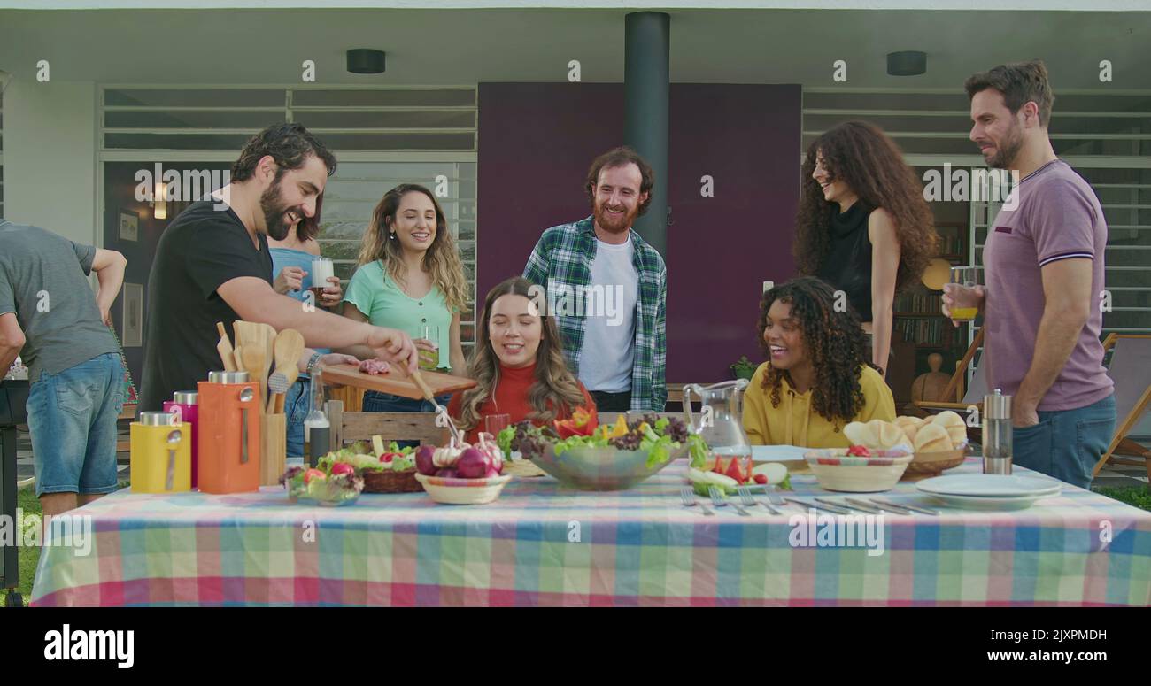 Group of happy people sitting at barbecue in home backyard. Friends ...