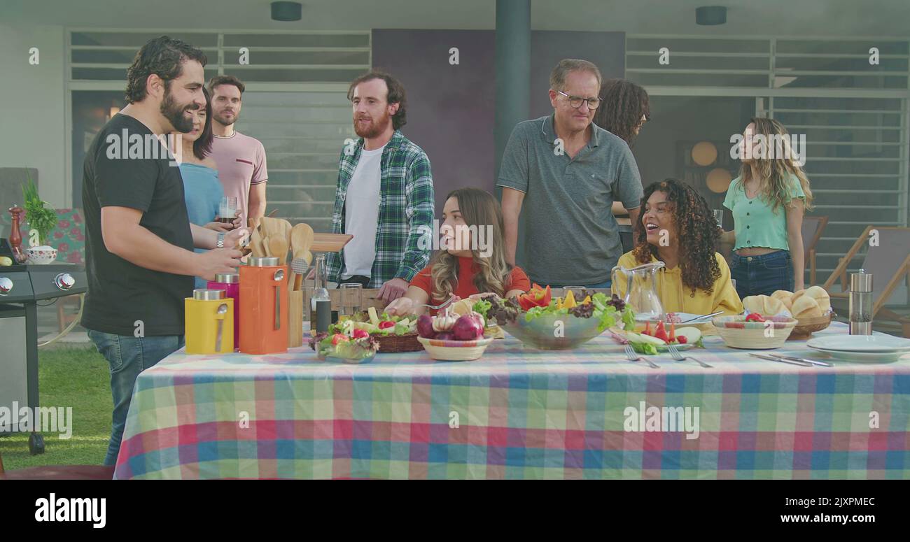 Group of happy people sitting at barbecue in home backyard. Friends ...