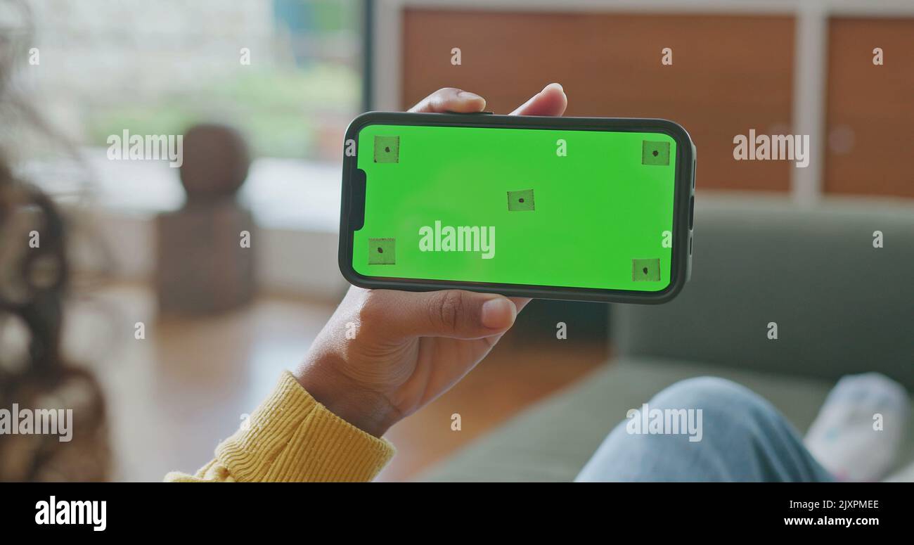 Closeup female hand holding smartphone horizontally with green screen ...