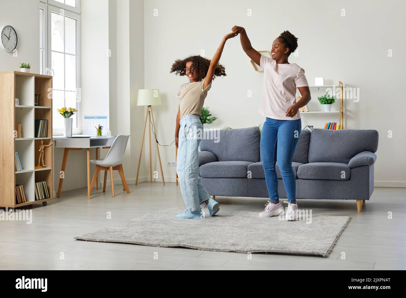 Young woman with her teenage daughter are dancing while enjoying ...