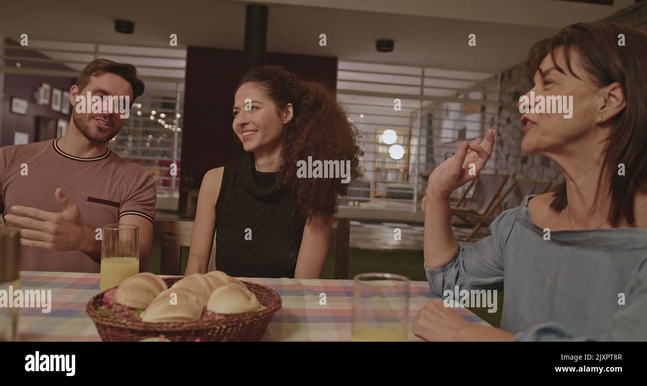 Friends and family share stories while sitting at the table in the ...