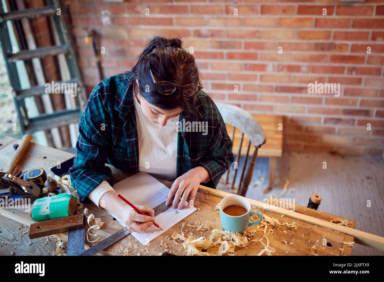 Young Female Carpenter Drawing And Measuring Woodwork Design In Garage ...