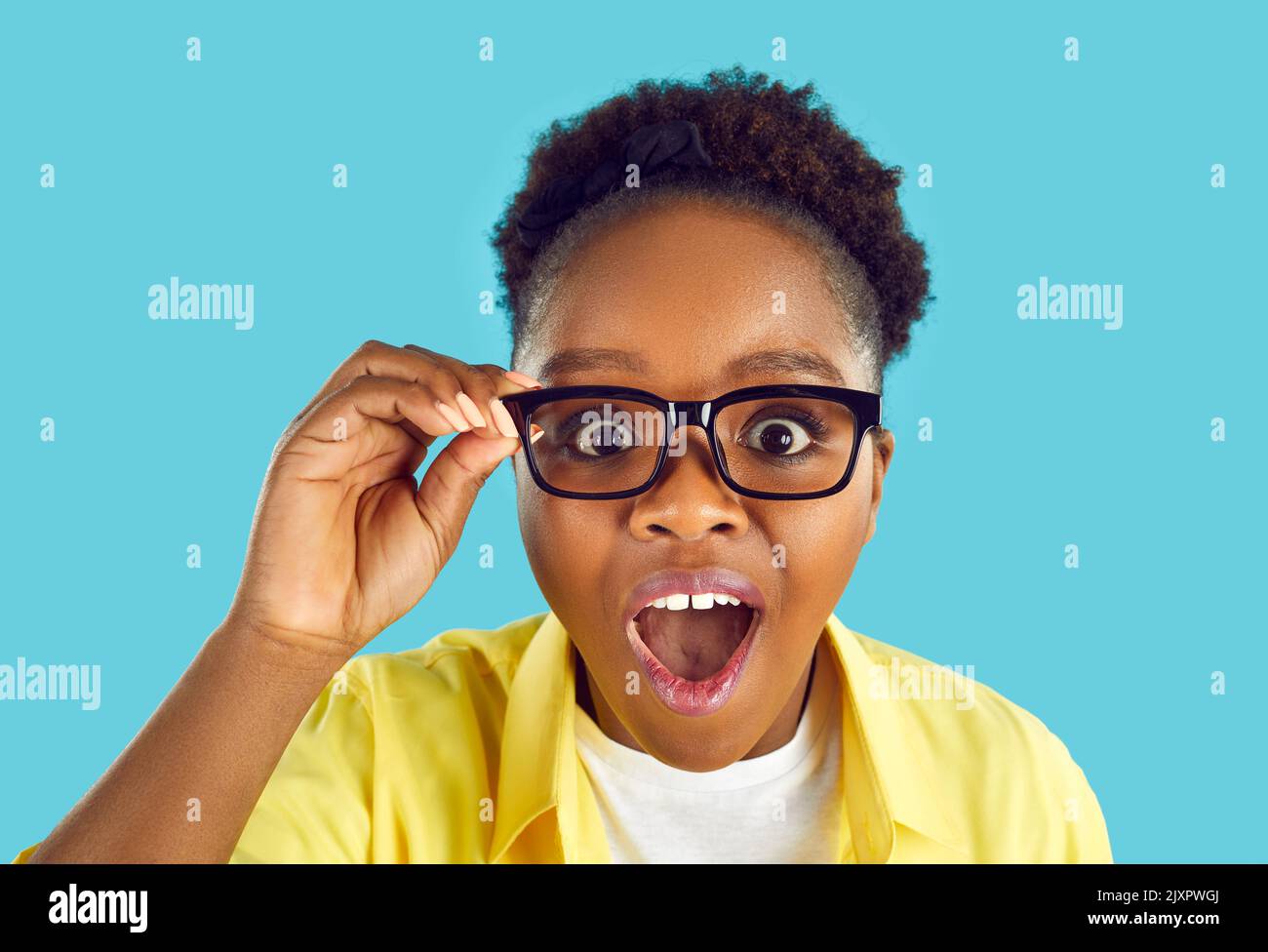African American woman in glasses looking at something with happy, surprised face expression ...