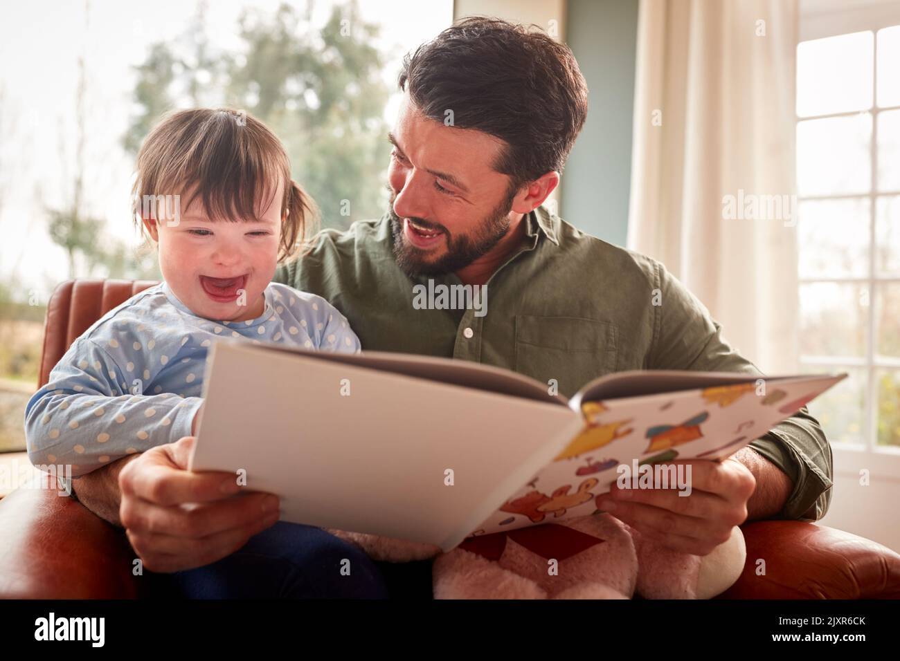Father With Down Syndrome Daughter Reading Book At Home Together Stock ...