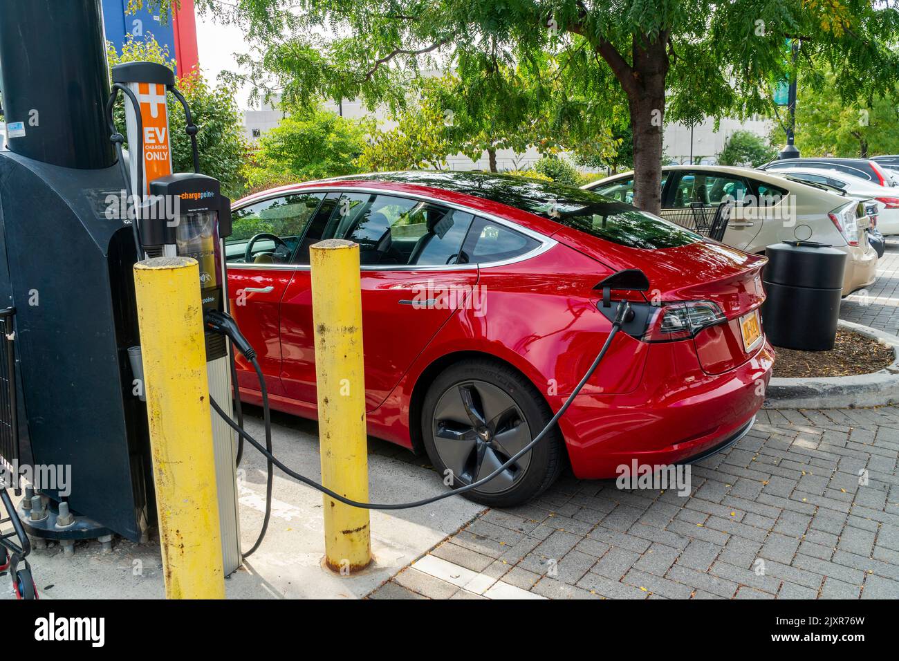 A Tesla electric vehicle is charged at a public charging station in ...