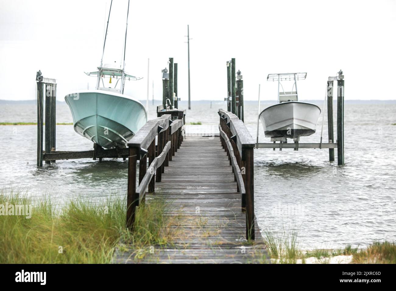 A small wood boat dock pier with two boats raised Stock Photo - Alamy