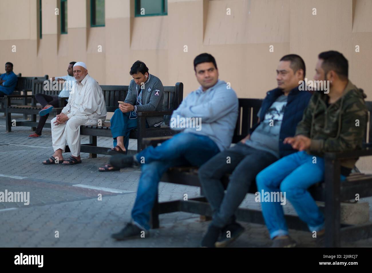 Men of all races and ages wearing light jackets sit on a series of ...