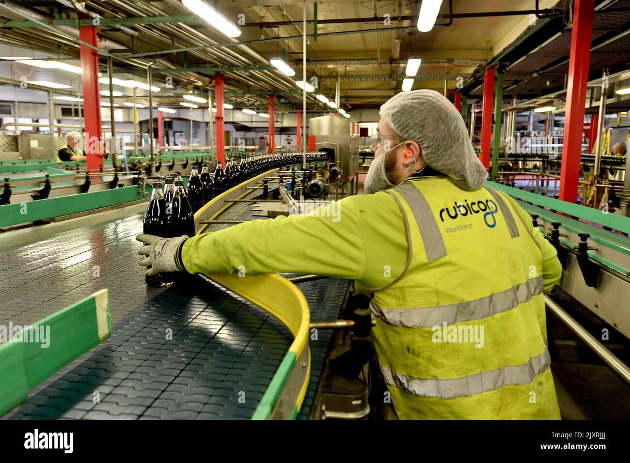 A Coca-Cola Amatil worker pushes bottles along a production line in ...