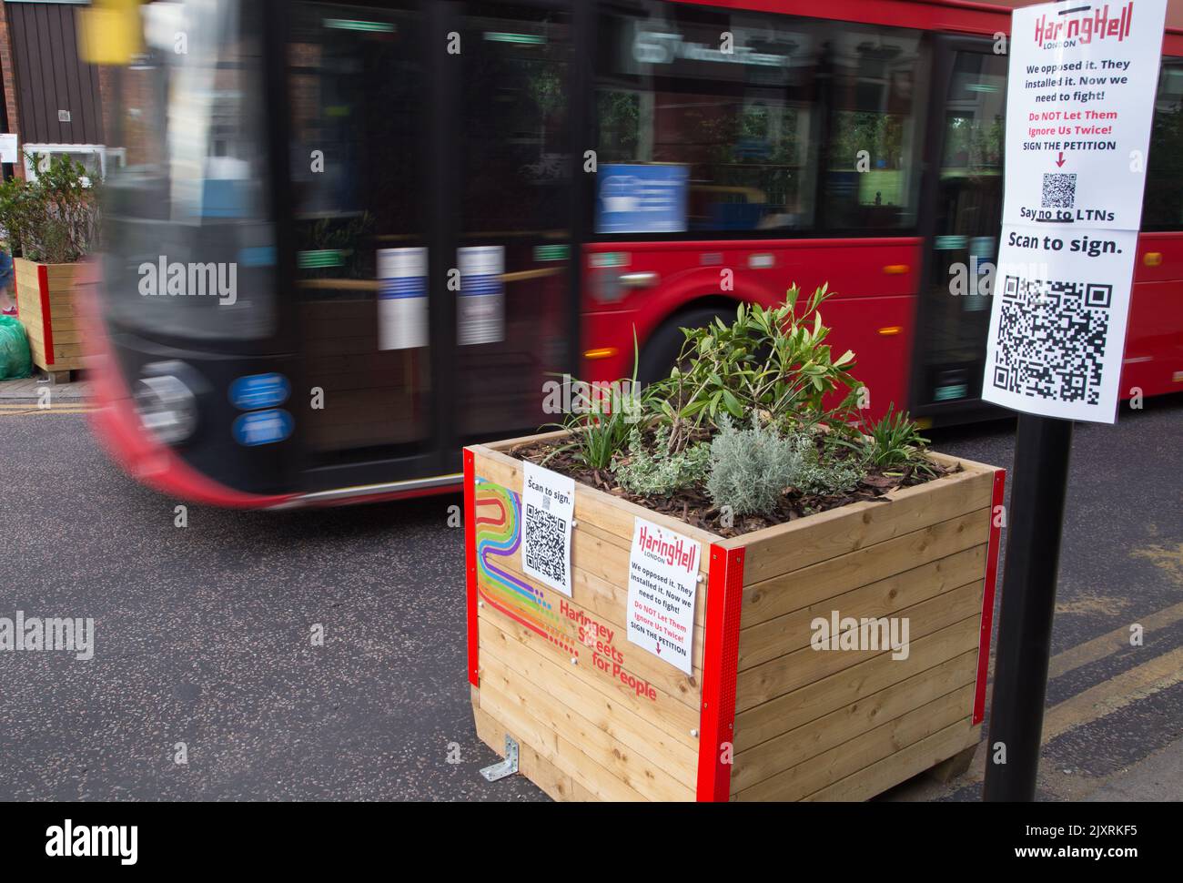 A red London bus passes through barriers signalling a controversial LTN ...