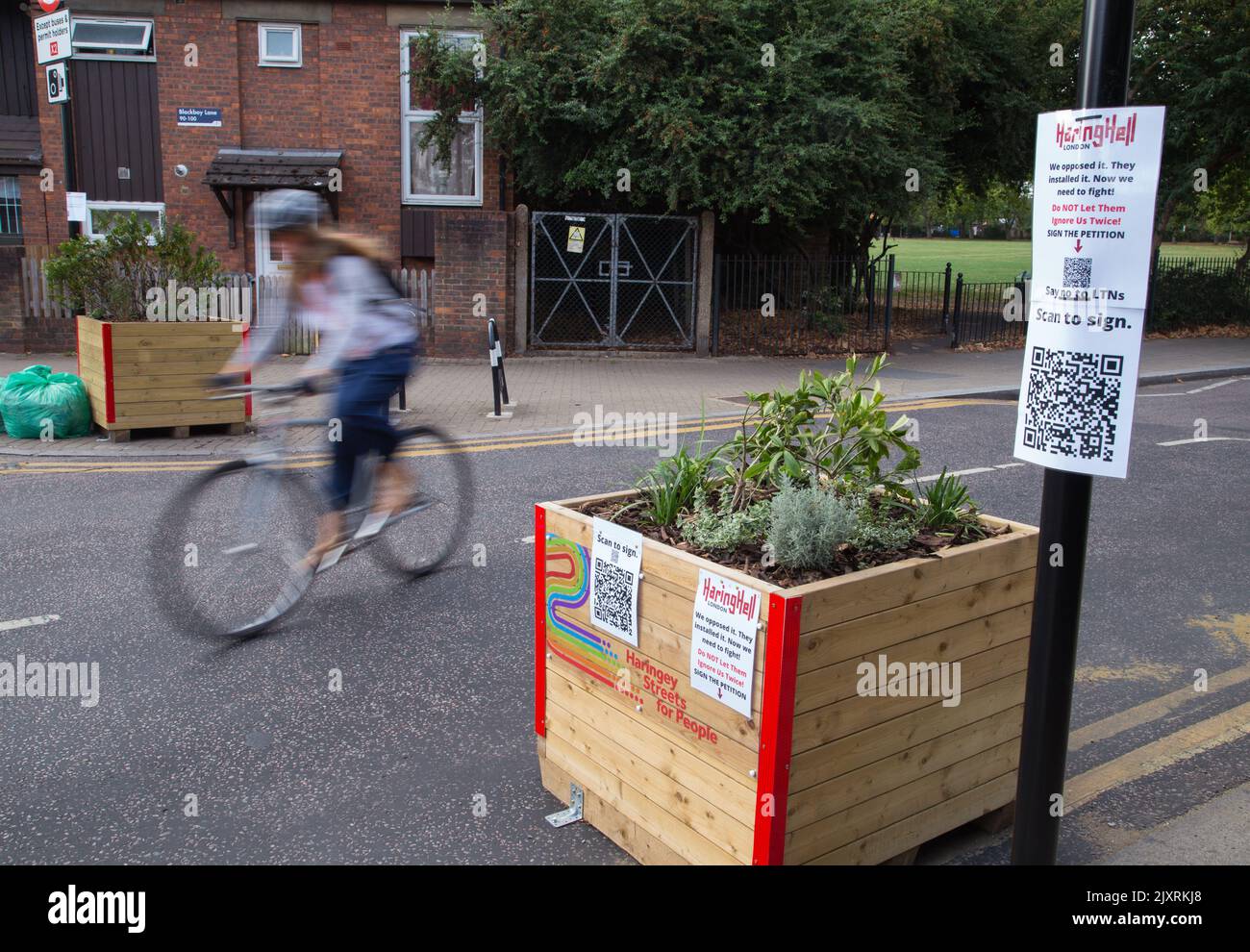 A female cyclist passes through barriers signalling a controversial LTN ...