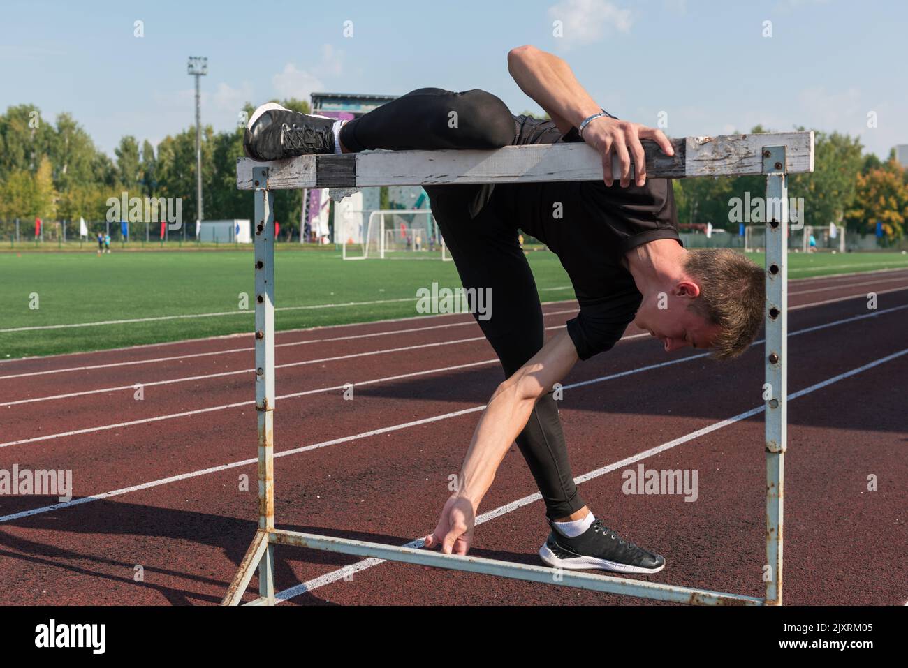 Young sporty man athlete runner in sportswear stretching before running ...