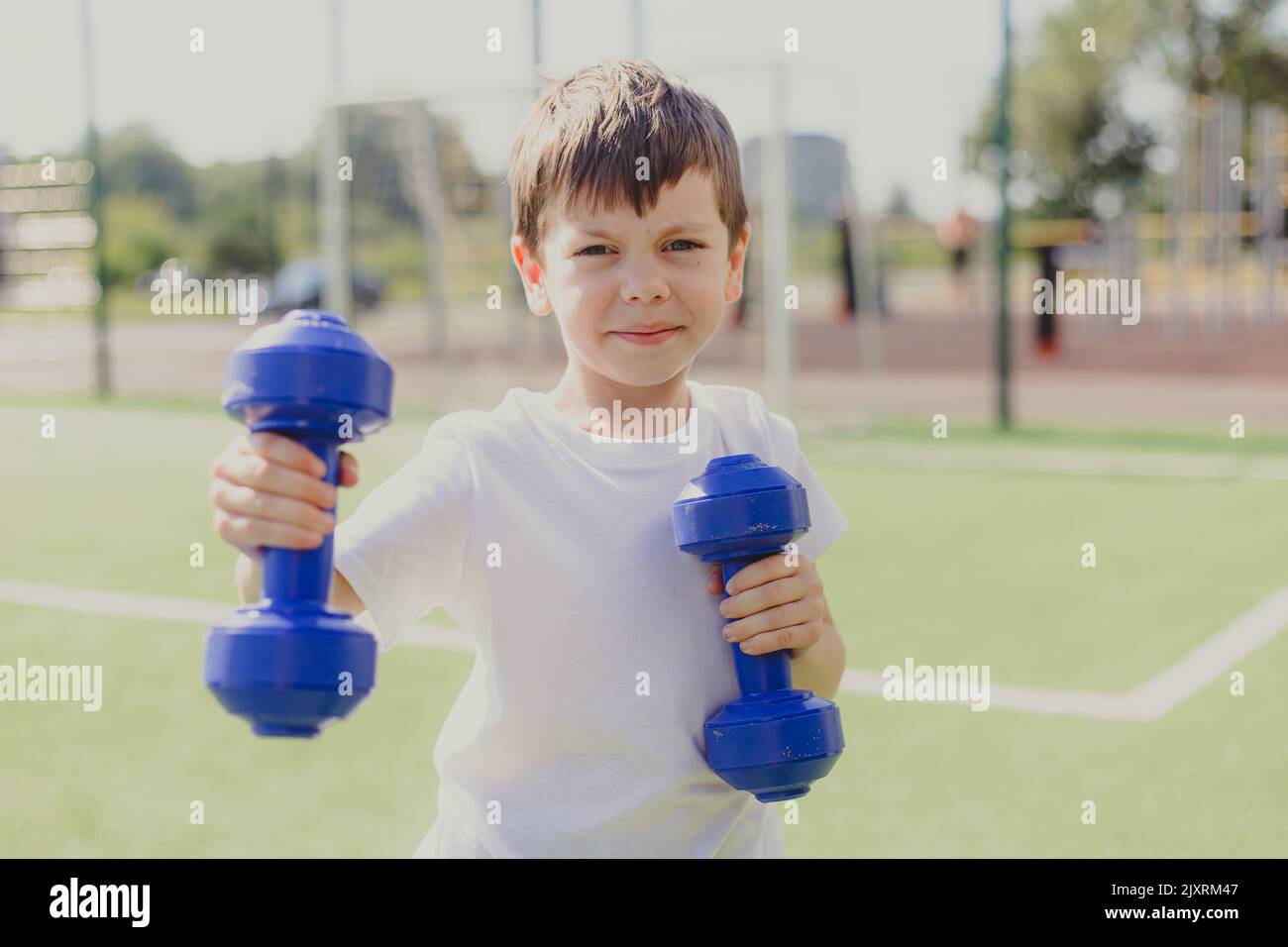 A child with dumbbells on the playground. A sporty kid. Illustrating an ...