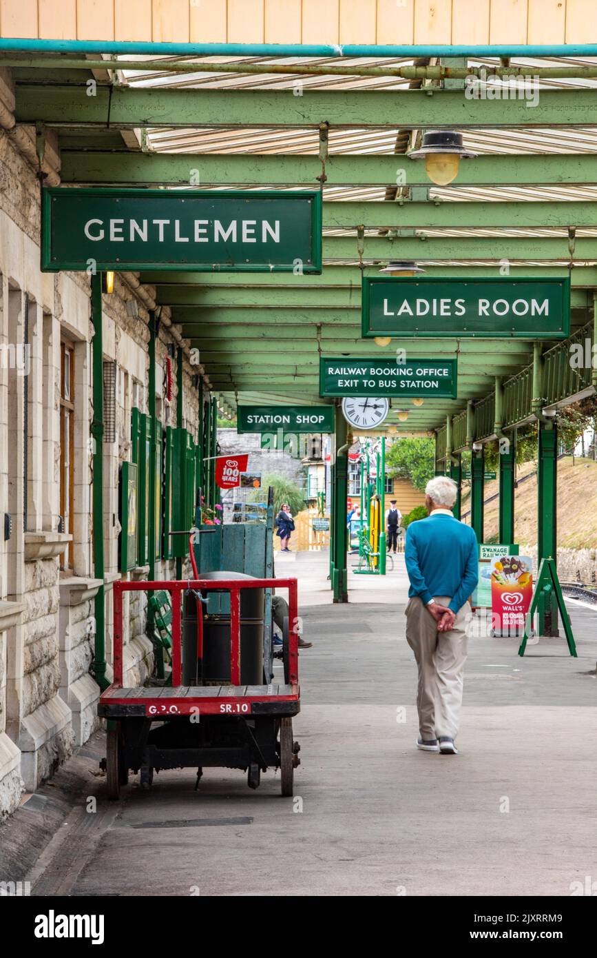 older man walking along the platform at swanage steam railway with ...