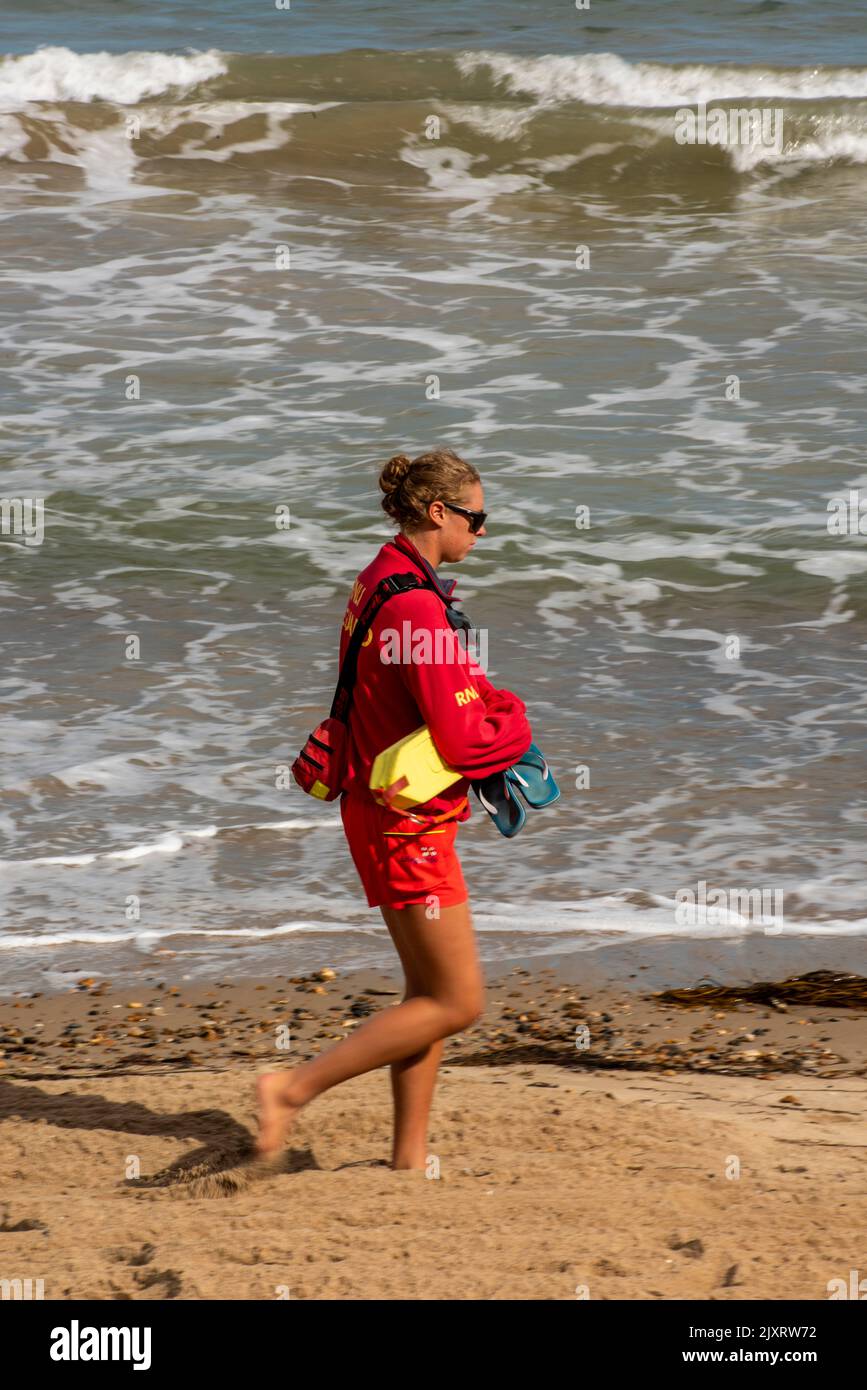 RNLI Lifeguard walking along sandy beach at wareham in dorset ...