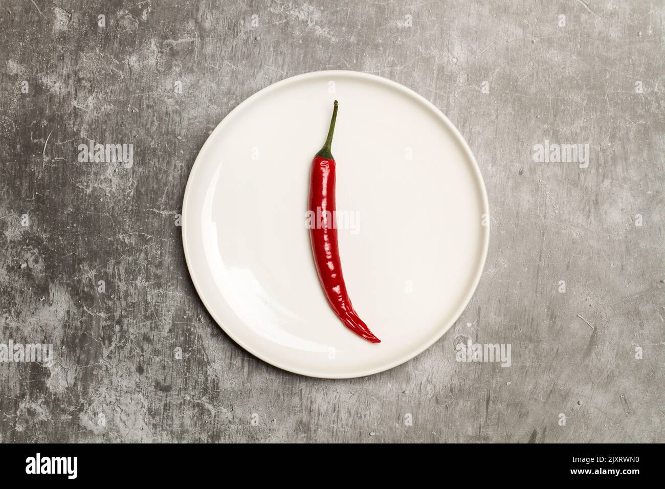 Red hot chili pepper in a white plate on a stone background in a top ...
