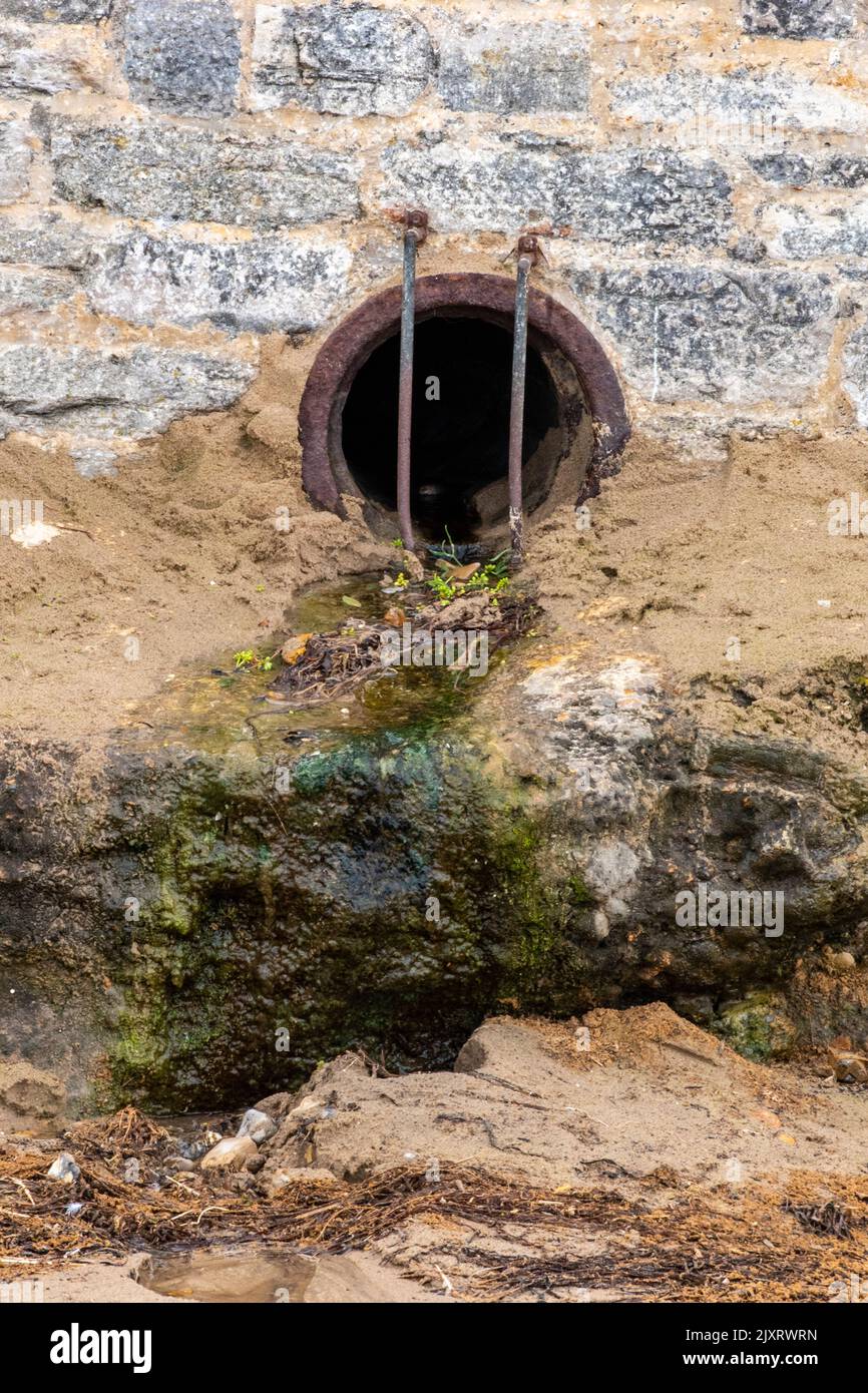 sewage outlet on a beach, overflow outlet onto sandy beach, water ...