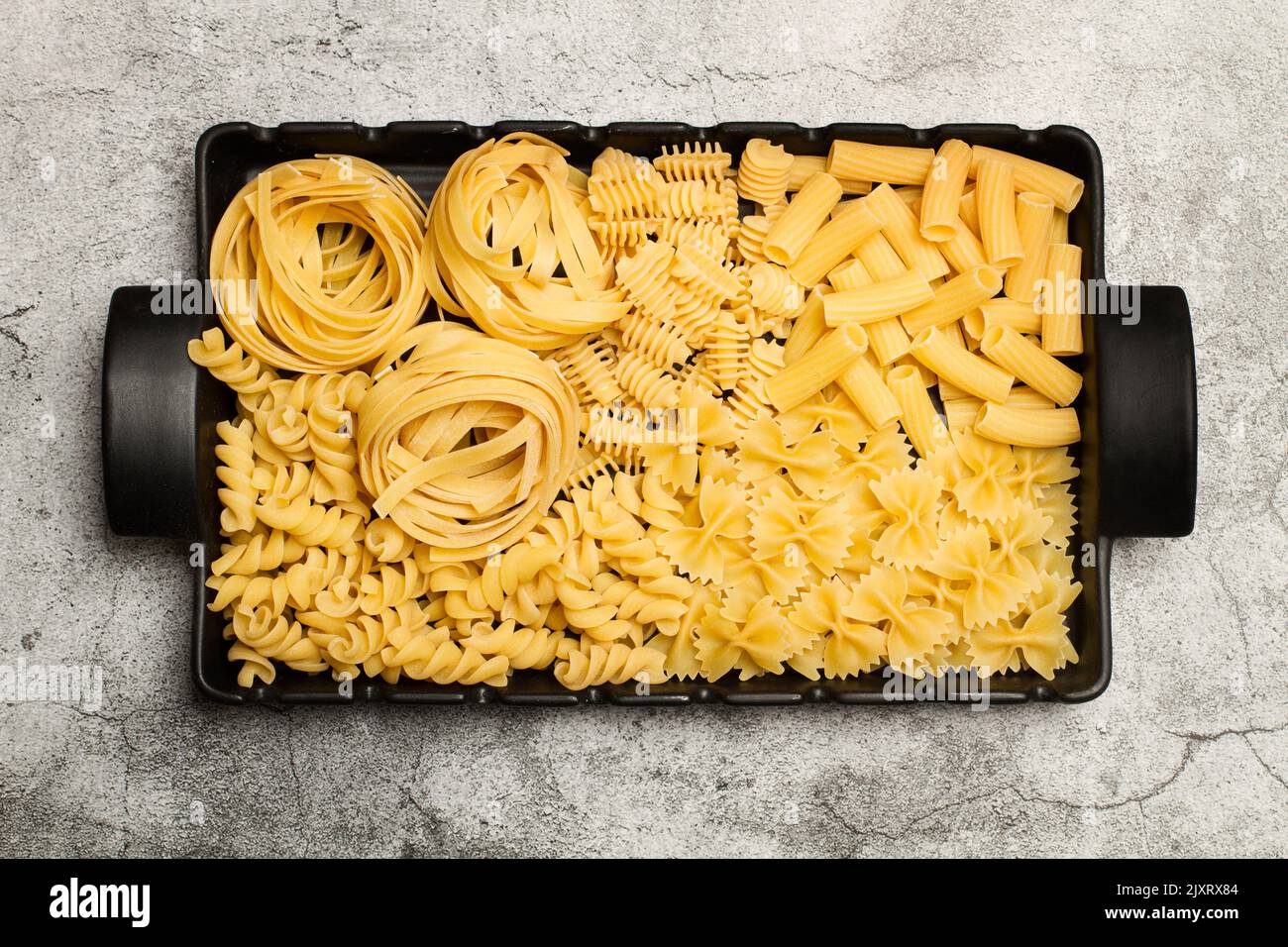 Assorted dry noodles in a rectangular black serving platter with ...