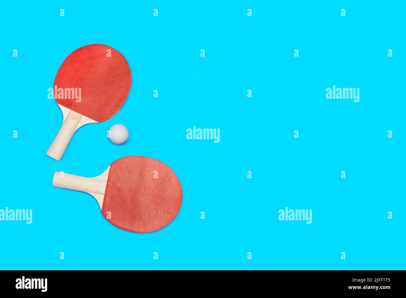 Red ping pong paddles and a white ball on a blue background with copy ...