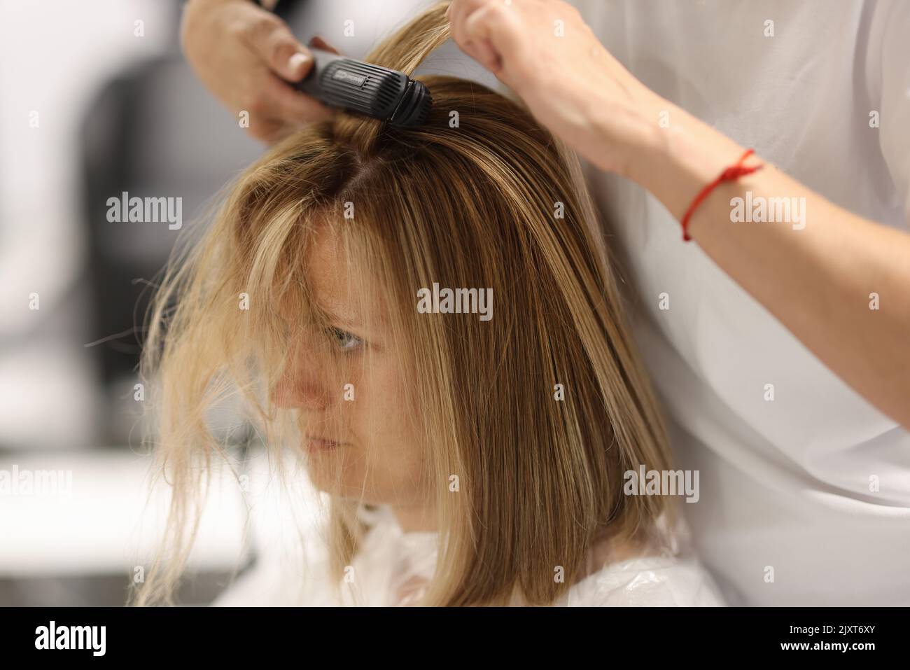 Pulling strands of hair with professional iron care Stock Photo - Alamy