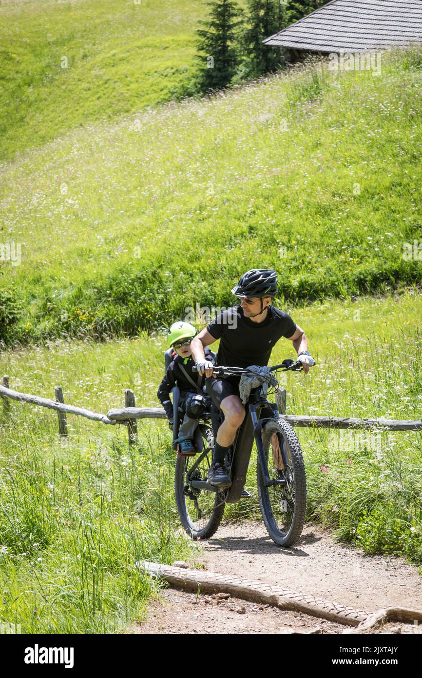 Man rides his e-bike up a steep mountain track with a young child on ...