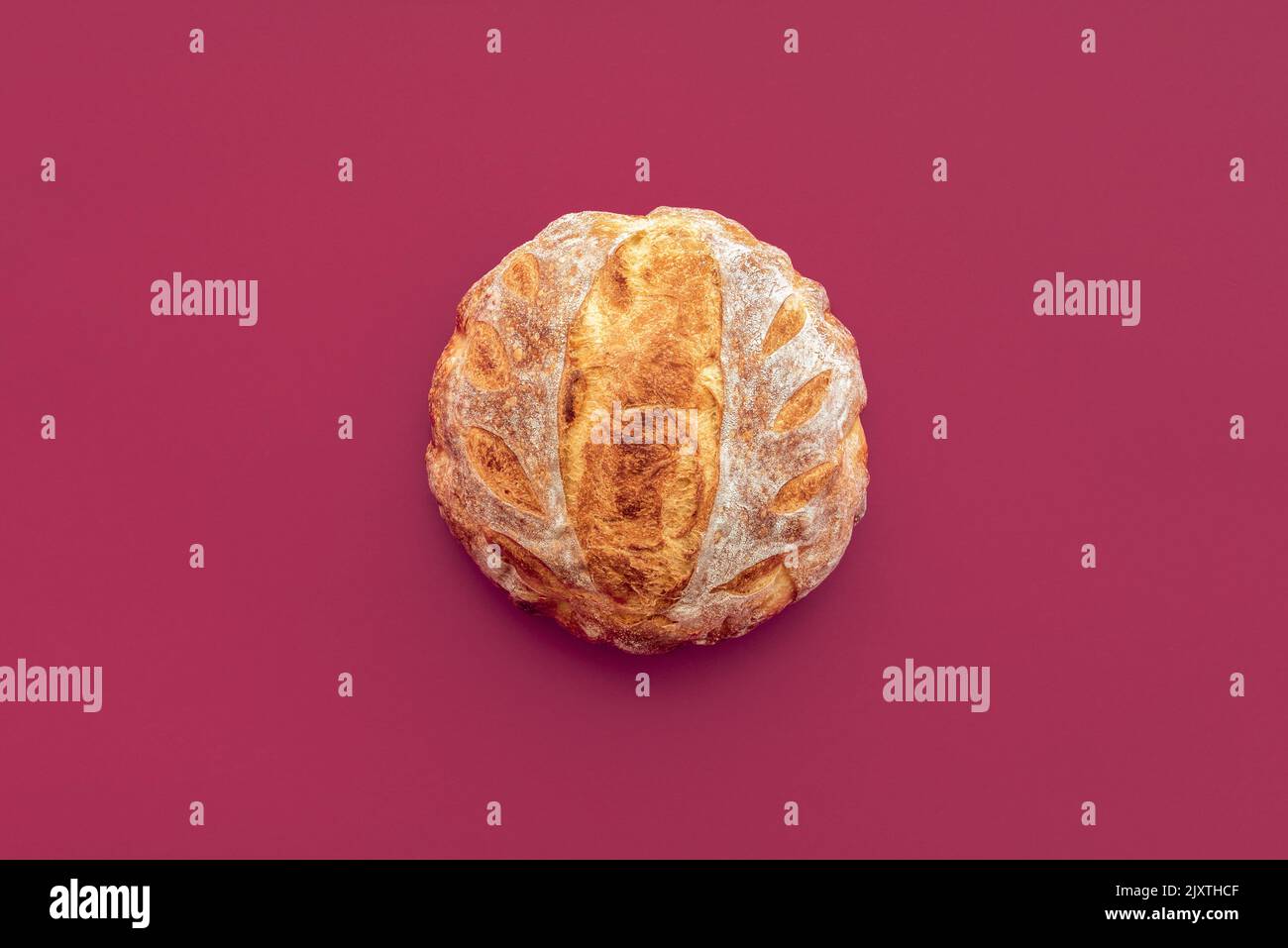 Above view with a freshly baked loaf of bread minimalist on a burgundy ...