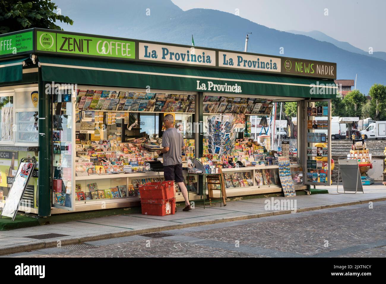 Man buying a paper from a small kiosk/shop selling drinks, papers and ...