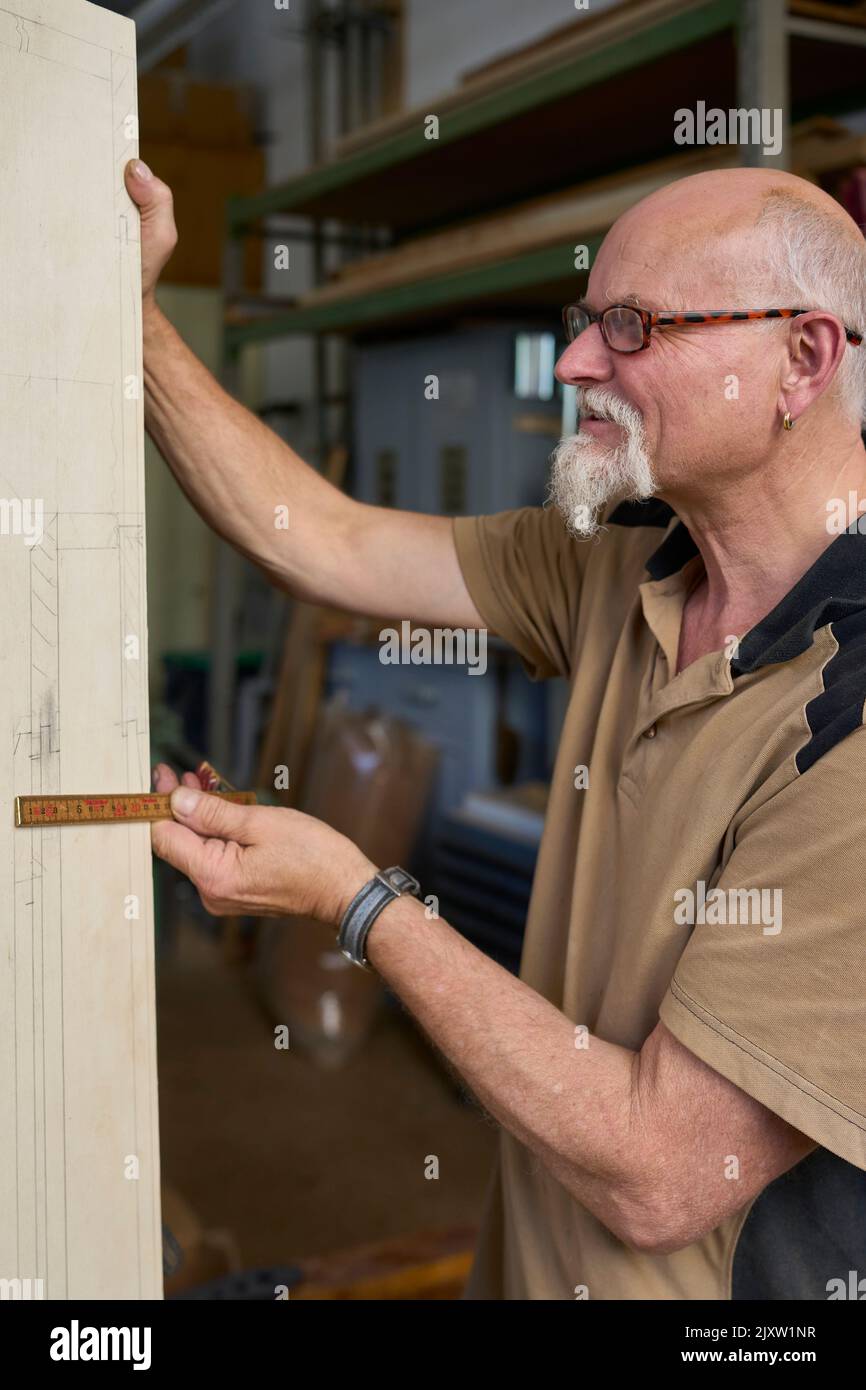 Carpenter Checks The Dimensions Of The Sketch Transferred To The Wood ...
