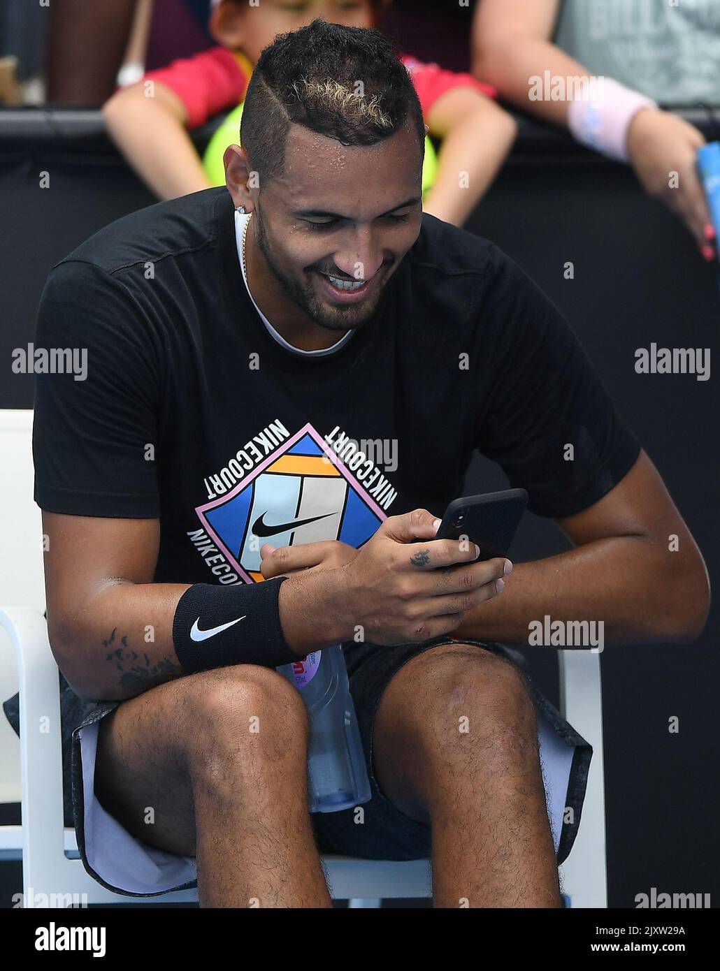 Nick Kyrgios of Australia looks at his phone as he trains on court 14 ...