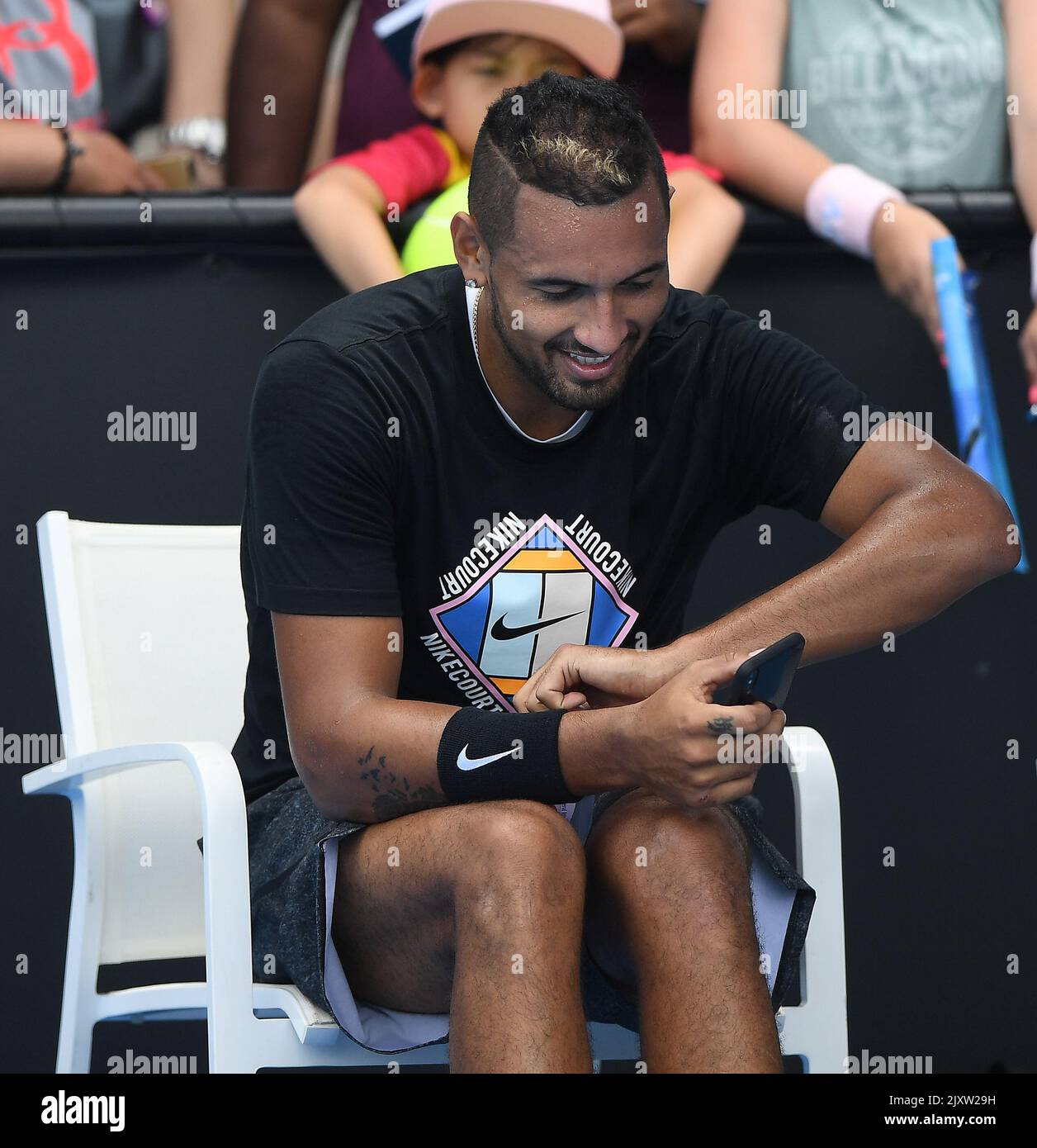 Nick Kyrgios of Australia looks at his phone as he trains on court 14 ...