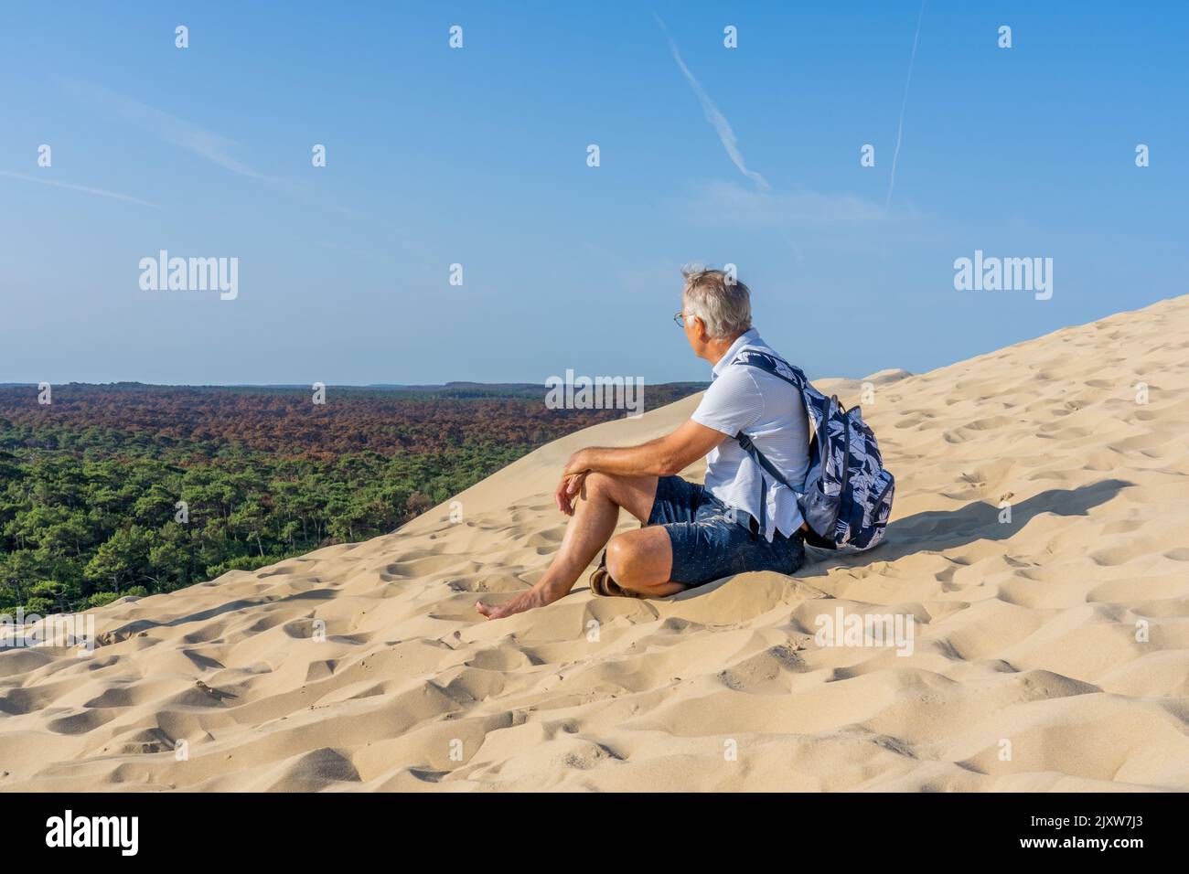 Man sitting on a huge sand dune, famous tourist destination Dune Pyla ...