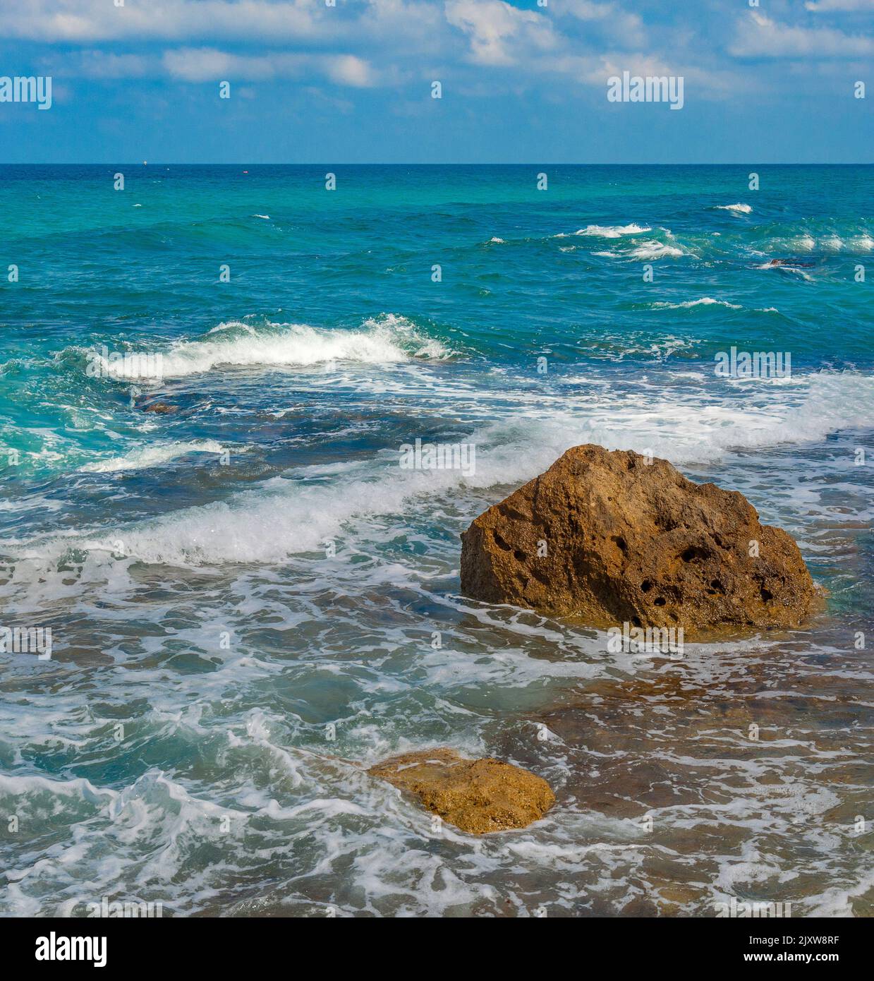 High tide in the Mediterranean Sea, warm, foamy waves run up the ...